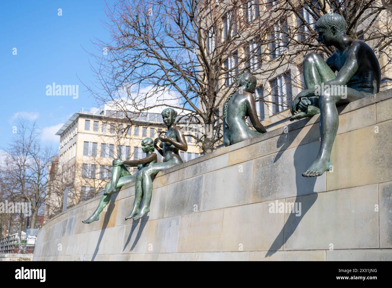 Three girls and a boy sculptures sitting on top of a stone wall at ...