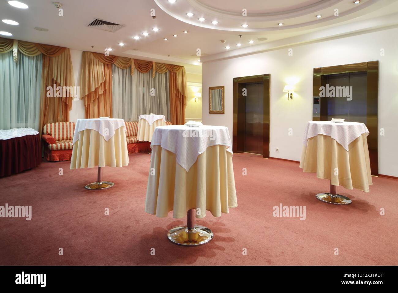 Simple tables with tablecloths, sofas in buffet at modern hotel and ...