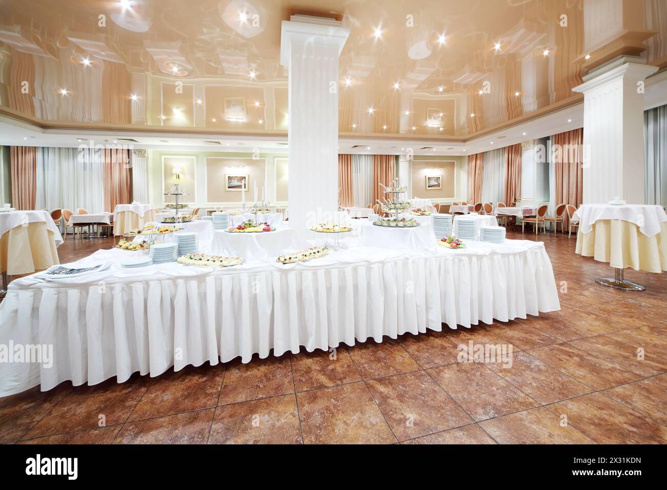Large buffet and small round tables with tablecloths in modern hotel ...