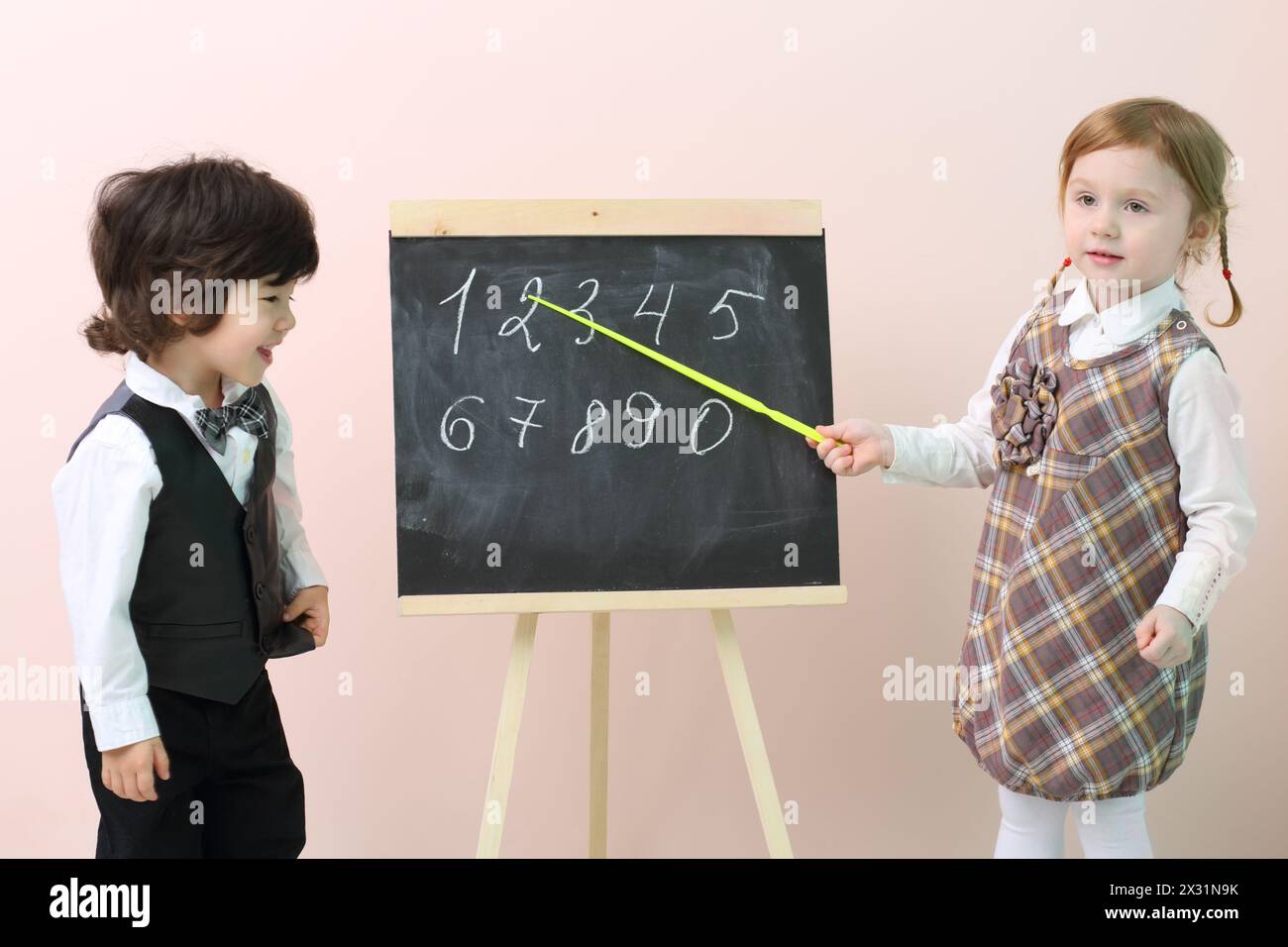 Little girl shows by pointer figures at chalkboard for boy in studio ...