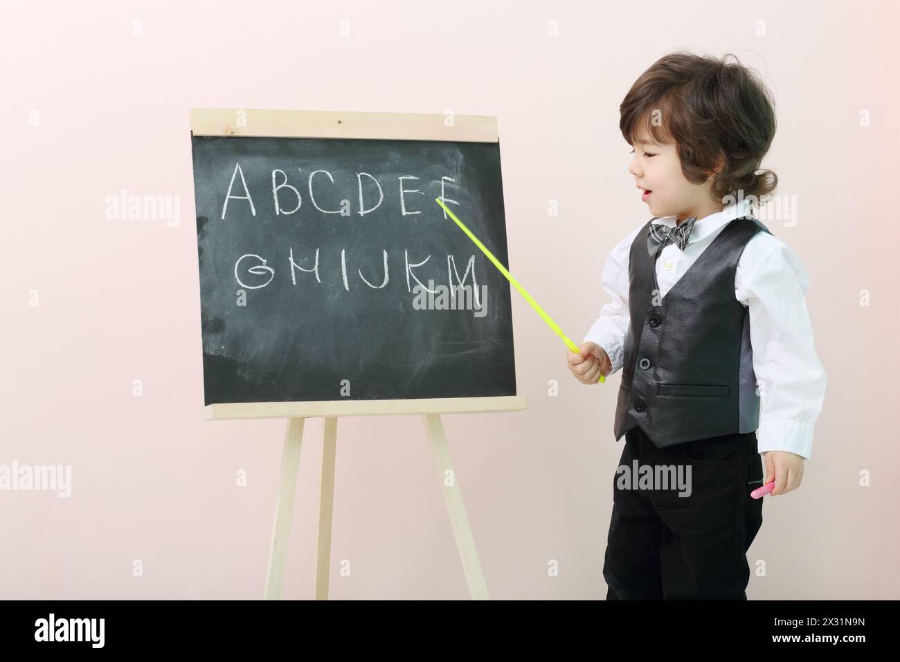 Little boy shows by pointer letters at chalkboard and talks in studio ...