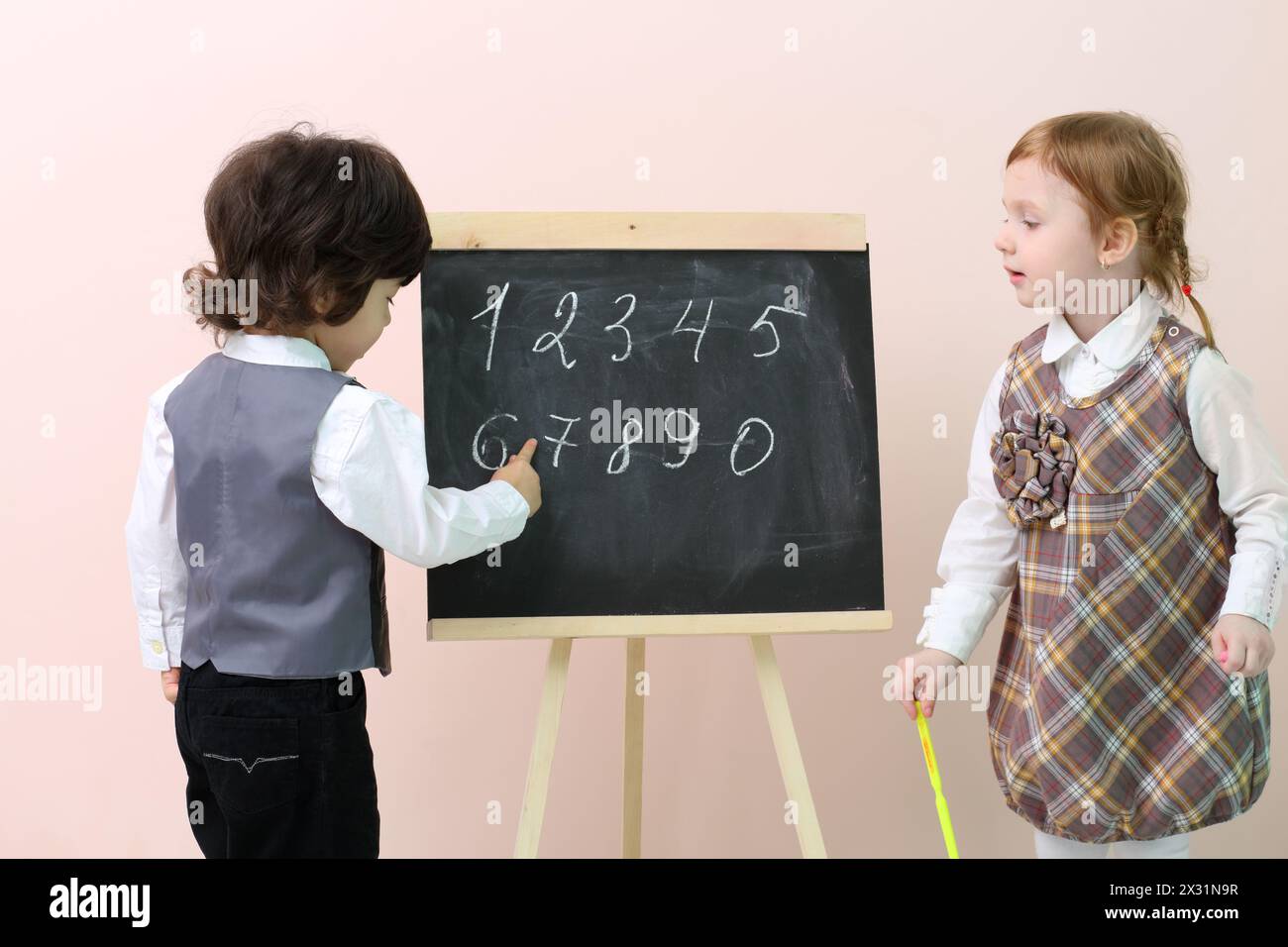 Little boy shows by finger figures at chalkboard for cute girl in ...