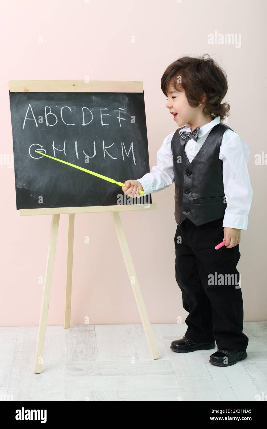 Little boy shows by yellow pointer letters at chalkboard and calls it ...