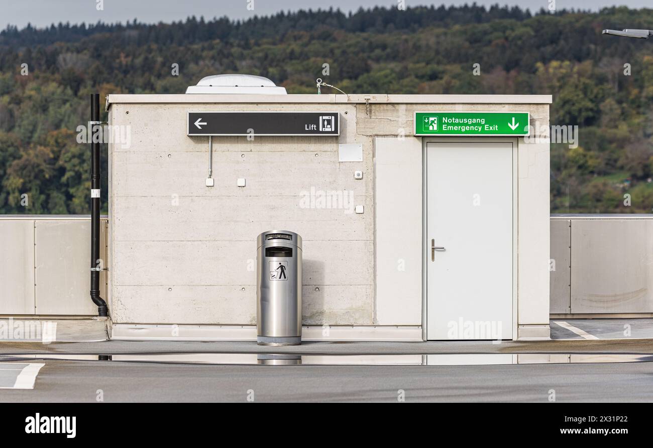Bei einem Parkhaus weisst ein schwarzes Schild den Weg zum Lift und ein ...