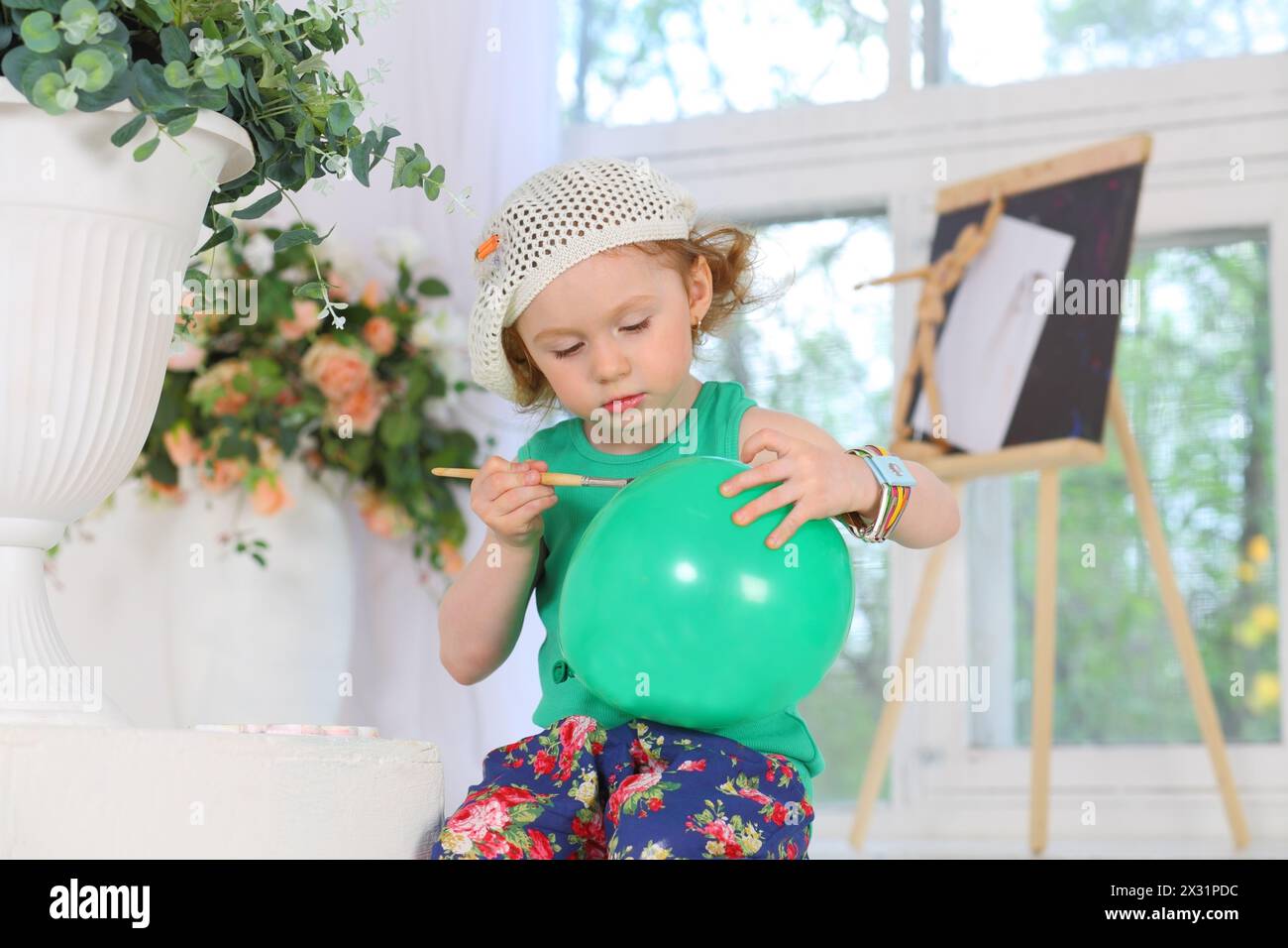 The little painter paints pictures on a green balloon Stock Photo - Alamy