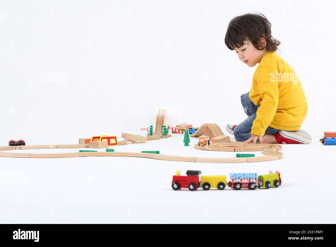 Little boy play with toy trains and big wooden railway on white ...