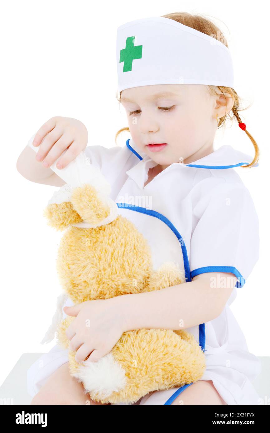 Little girl dressed as nurse bandages head to toy rabbit isolated on ...