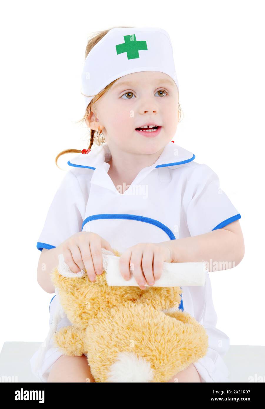 Little girl dressed as nurse bandages head to toy rabbit and looks away ...