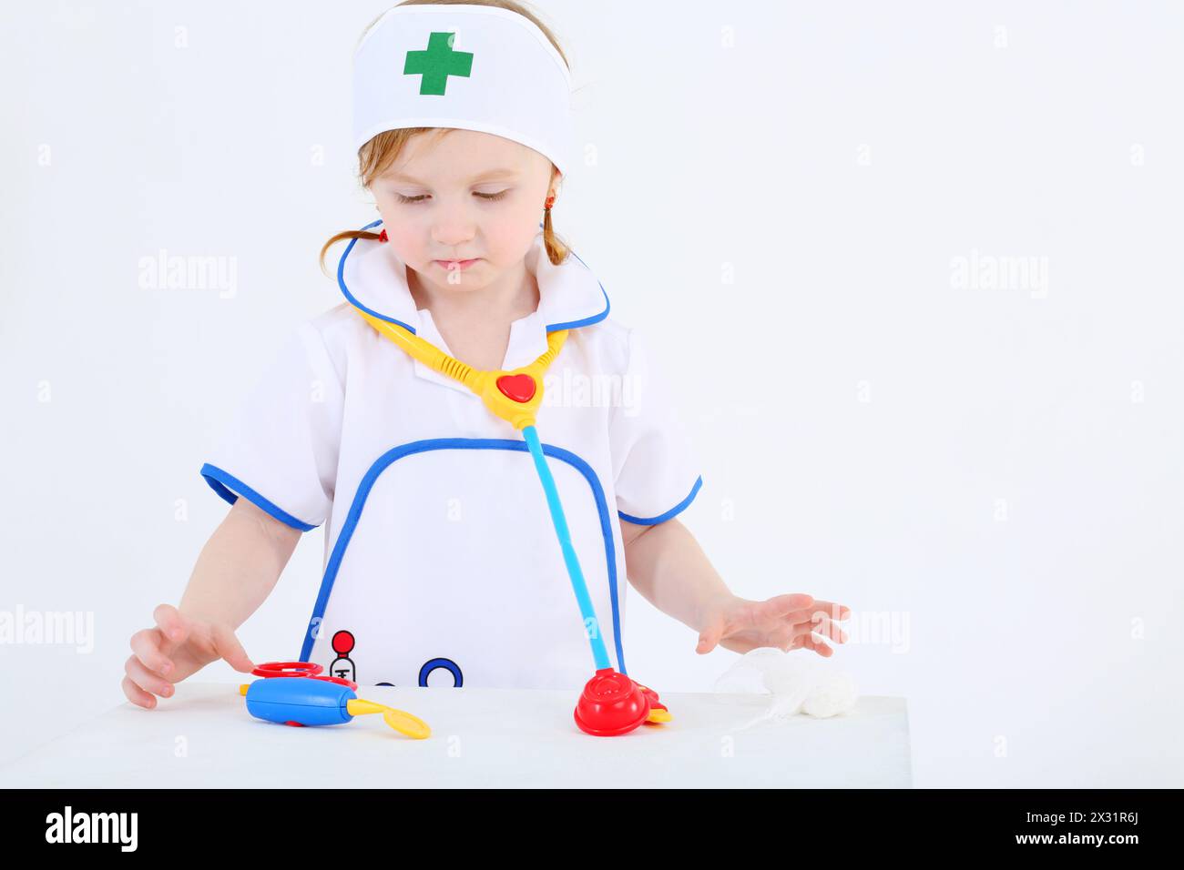 Little girl dressed as nurse plays with toy medical instruments on ...