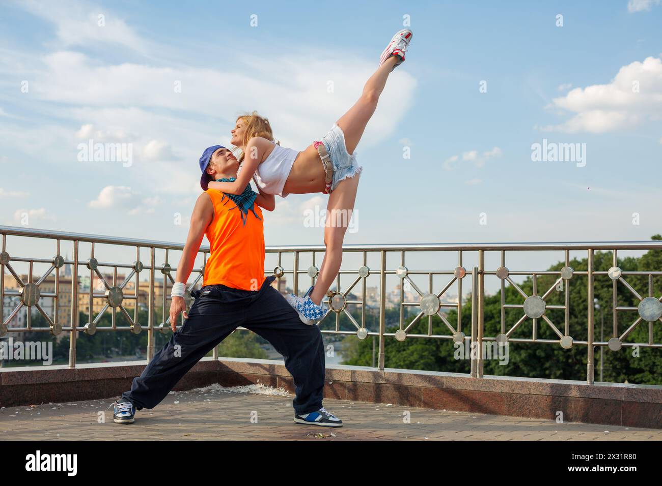 Young pair dancing modern dance in the street, girl staying on mans ...