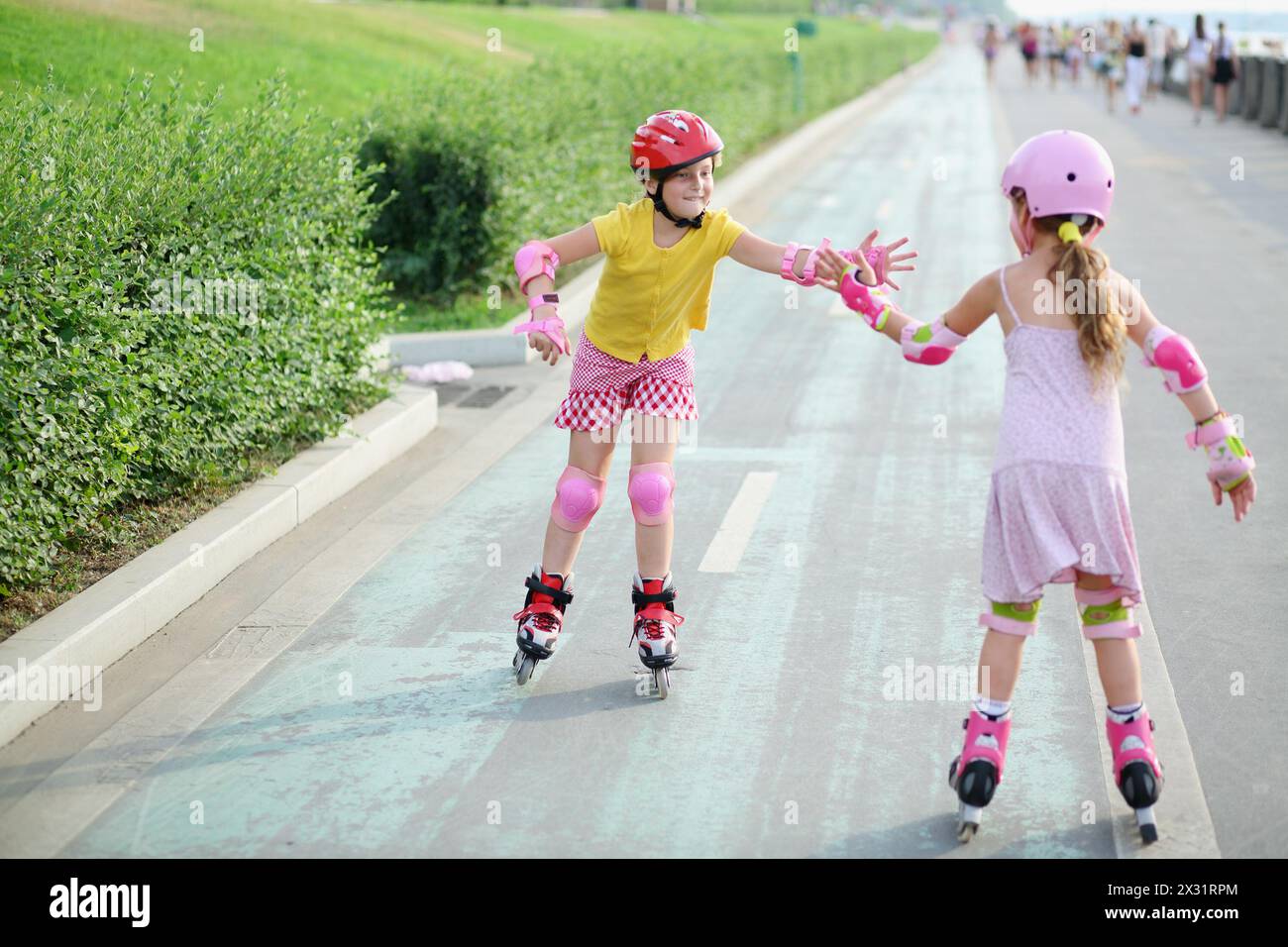 Two girls in roller skates, knee and elbow pads ride on rollers and ...