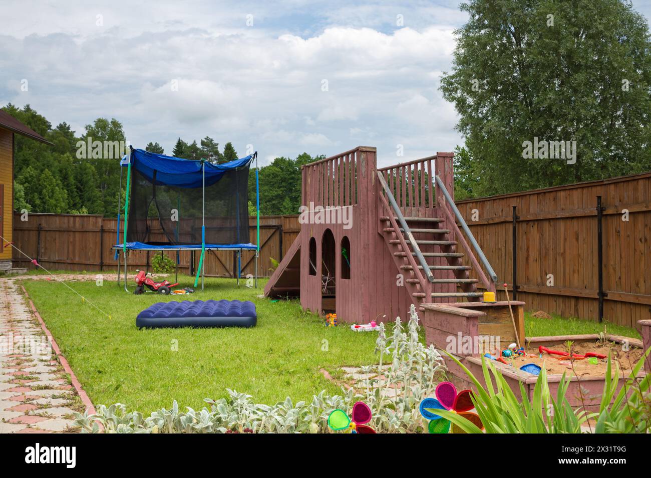 A childrens slide, trampoline and sandbox on the playground in the ...