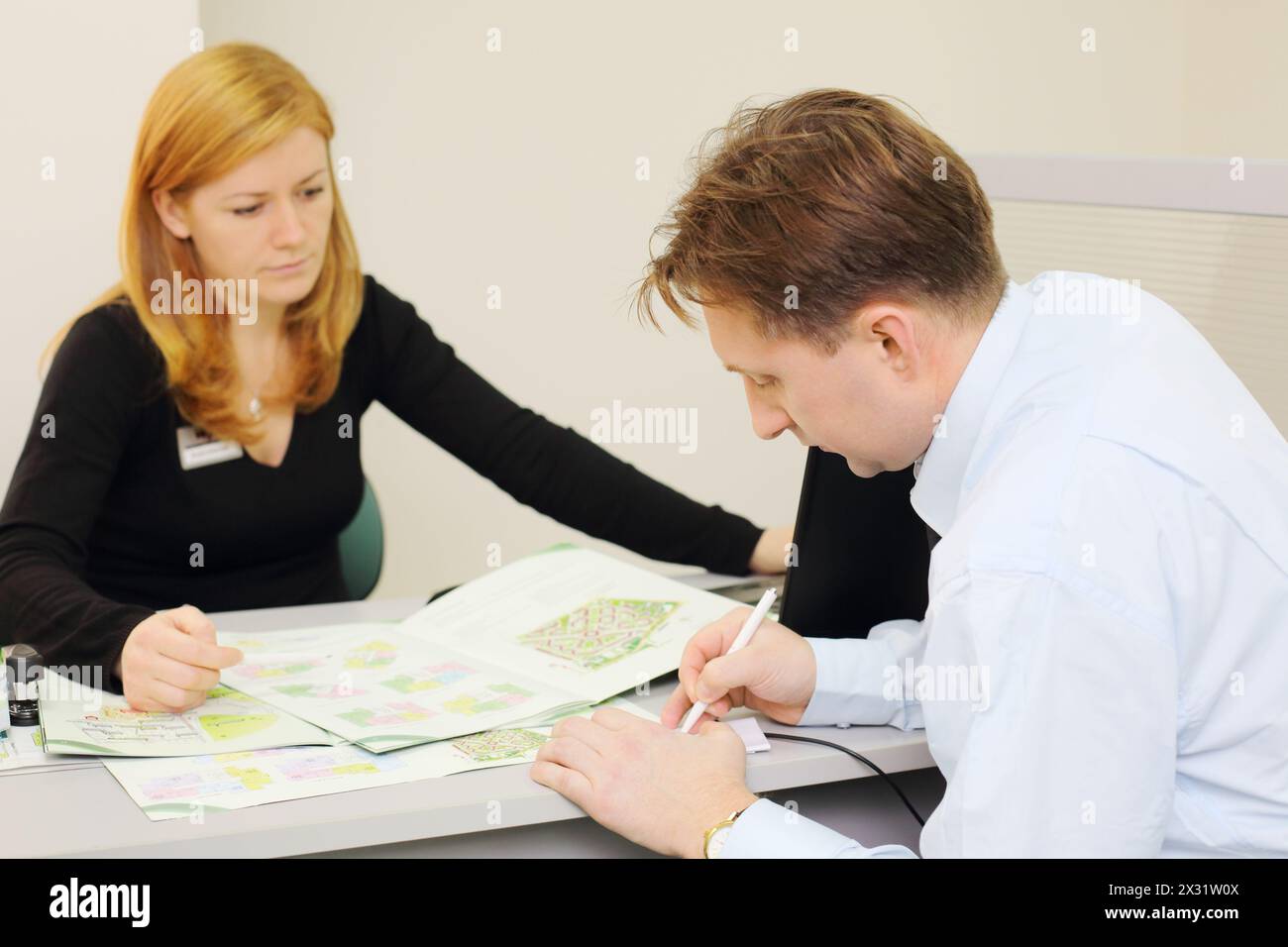 Man takes note and realtor looks at him in office. Focus on man Stock ...