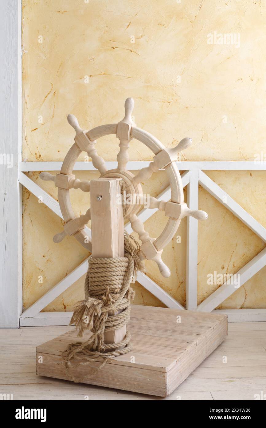 Beautiful wooden ship wheel with wire rope in light room with yellow ...
