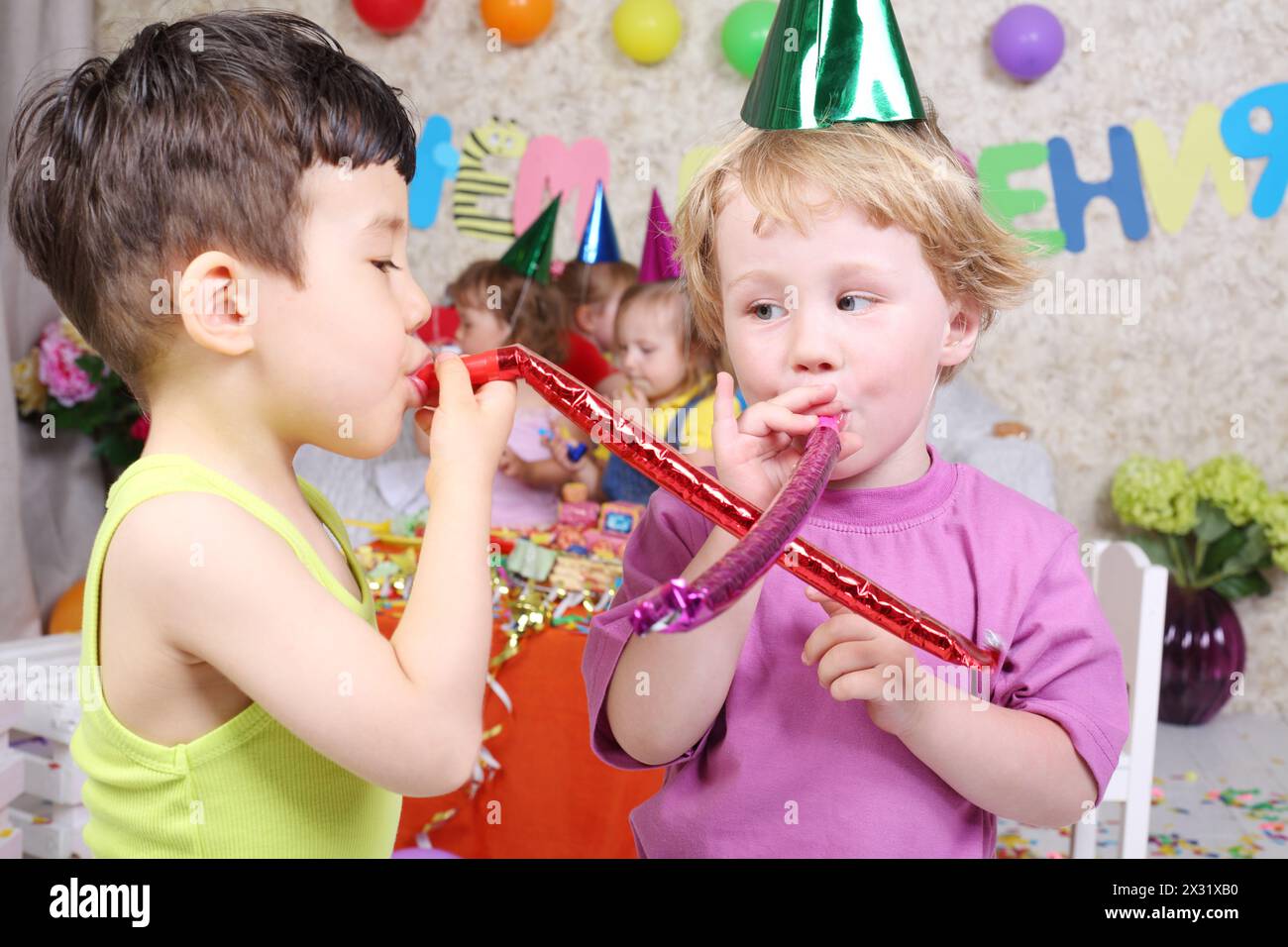 Two boys blow in party blowers at birthday party and three girls fun ...