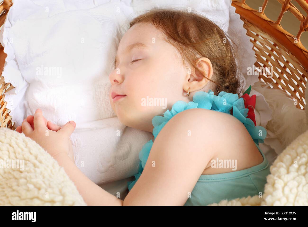 Pretty little girl sleeps under blanket in big wicker basket Stock ...