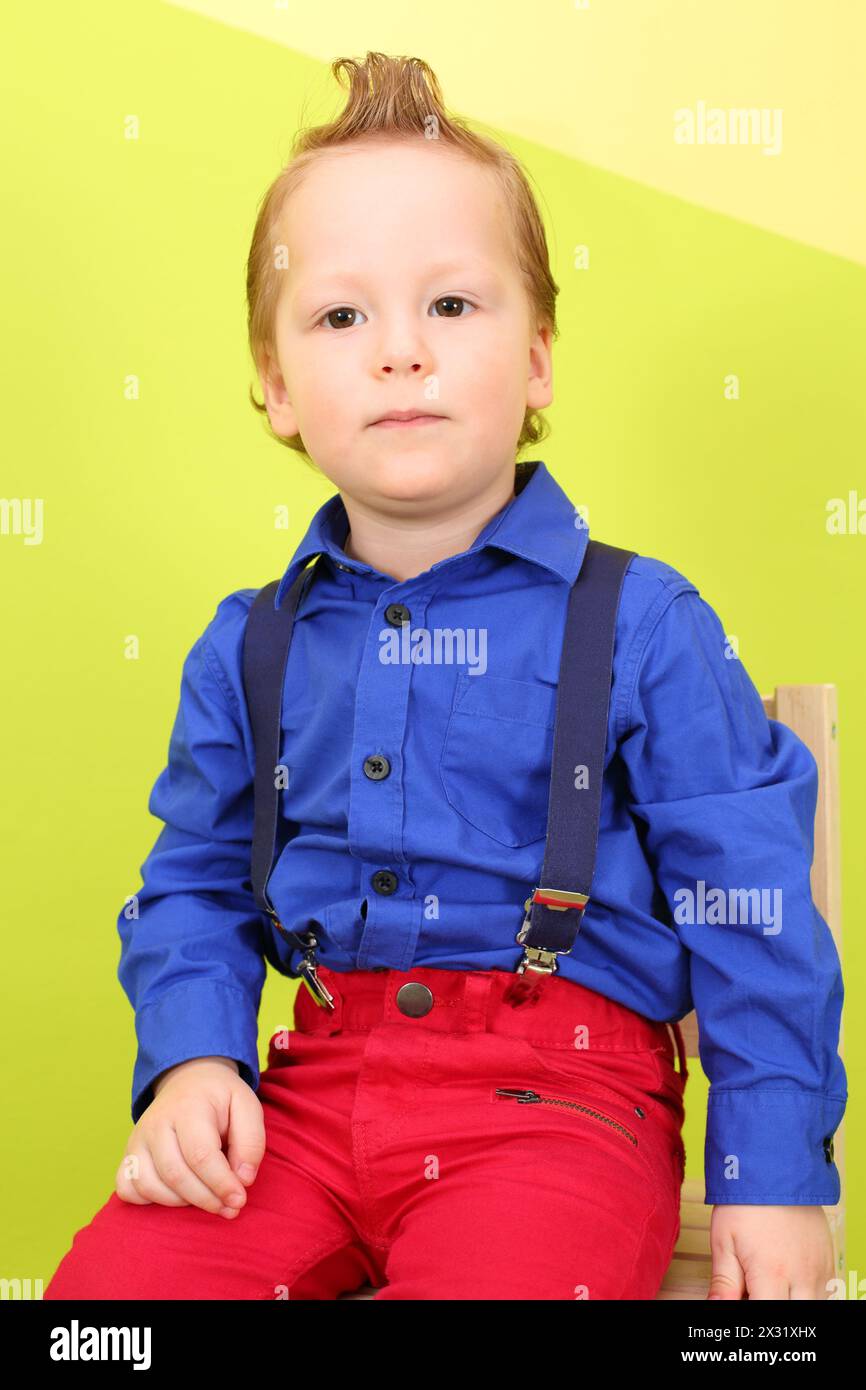 Mod boy in bright clothes sits on a background yellow and green wall ...