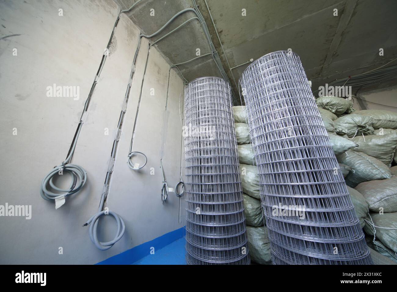 Rolls of metal grating and sacks of construction materials in the room ...