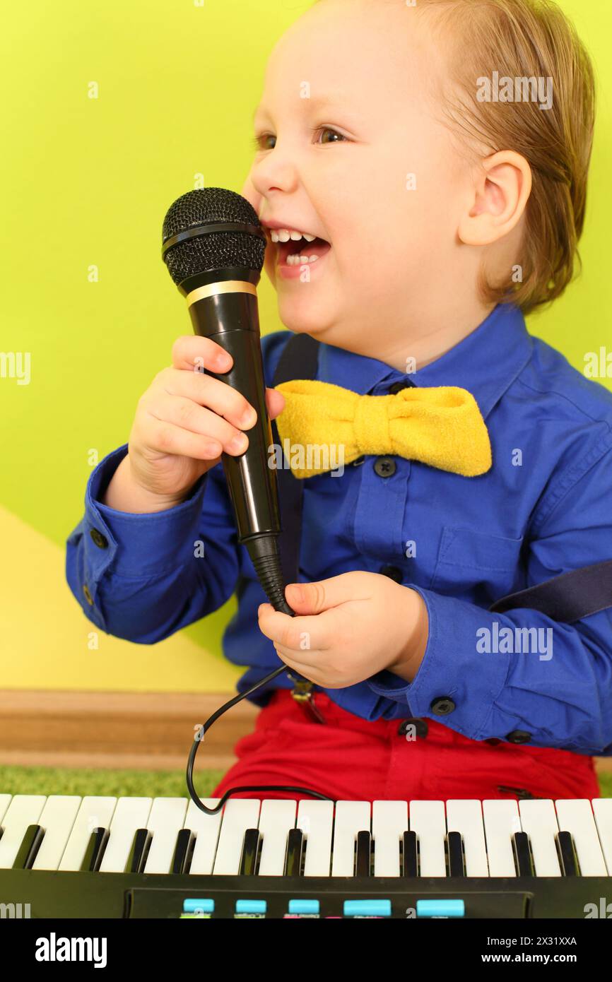 Boy in bright clothes with a toy piano singing into a microphone Stock ...