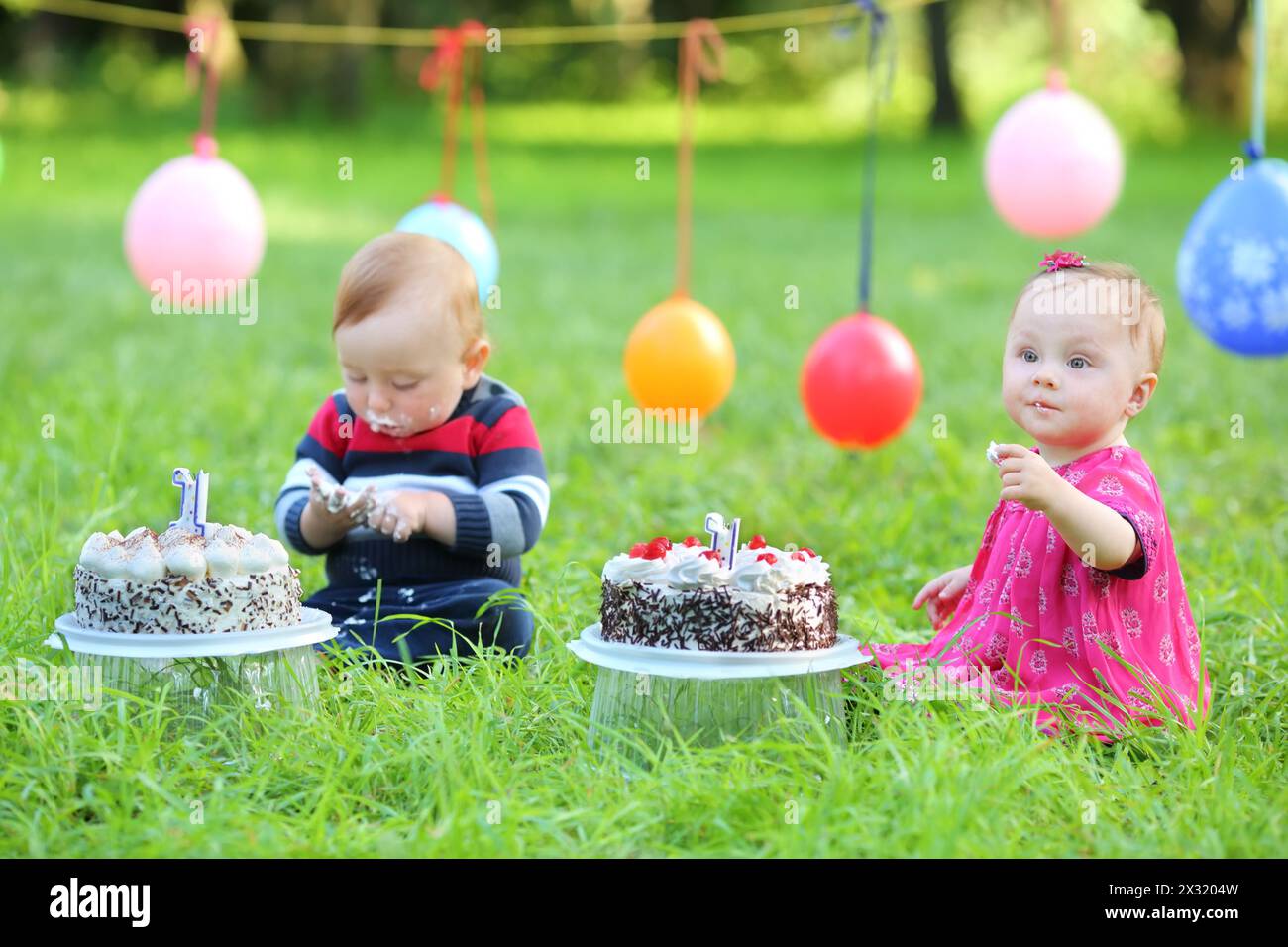 Little boy and girl eating cake at the celebration their first birthday ...