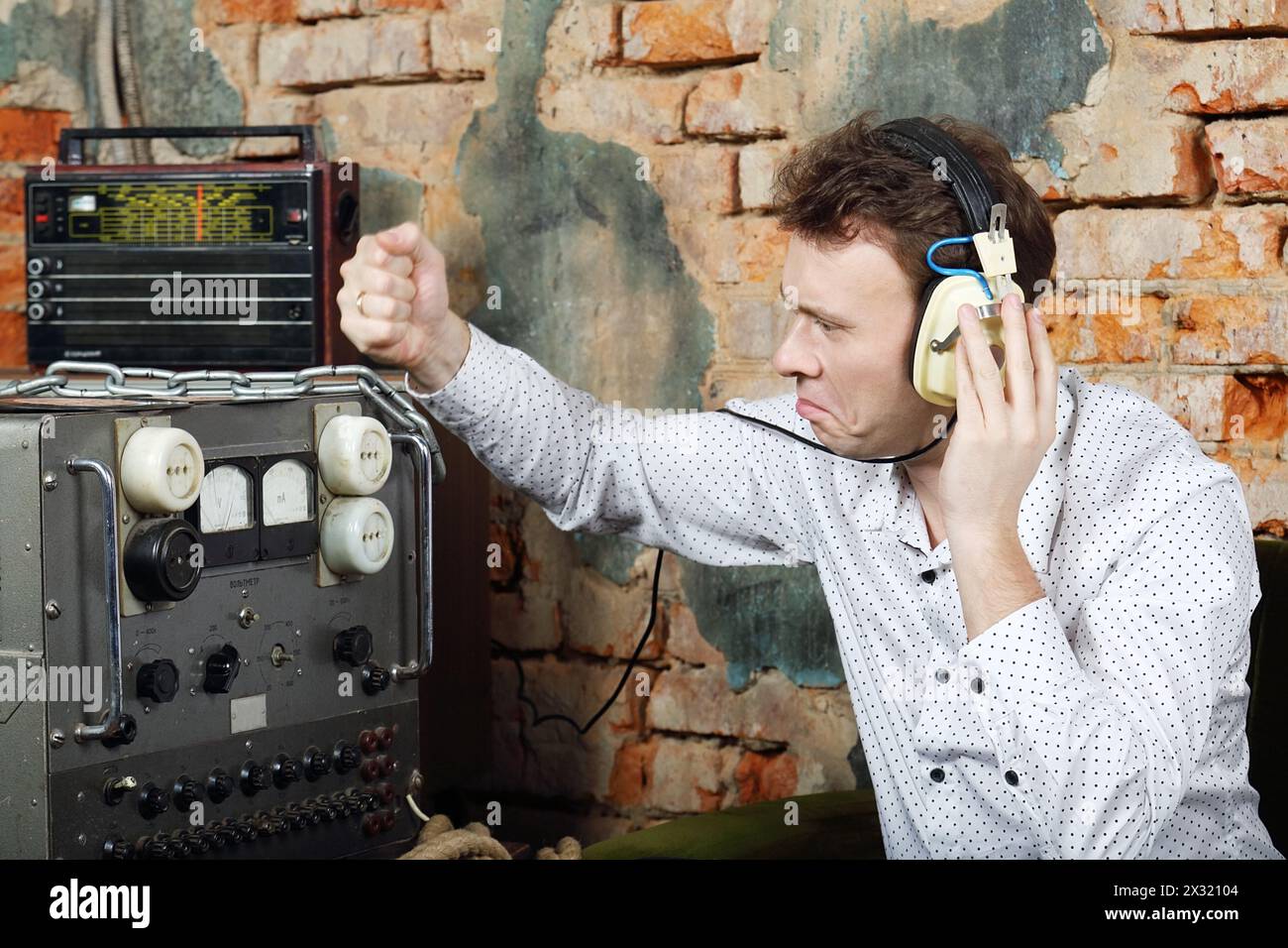 Man in big white headphones knocks on power source to radio receiver in ...
