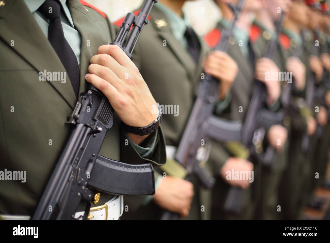 Hands and chests of soldiers in uniforms with machine guns on parade ...