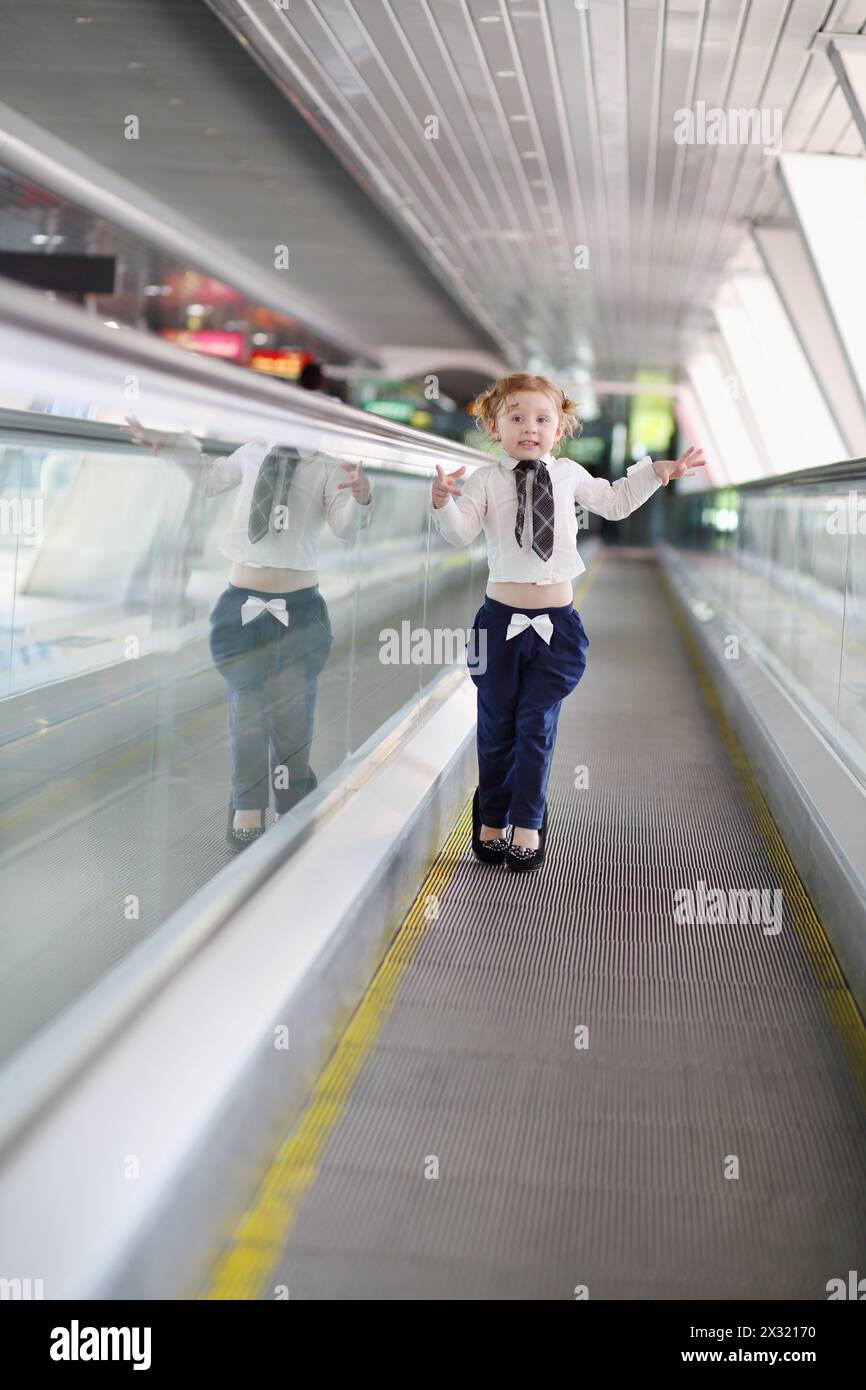 Little funny cute girl in mother shoes walks at long travelator Stock ...