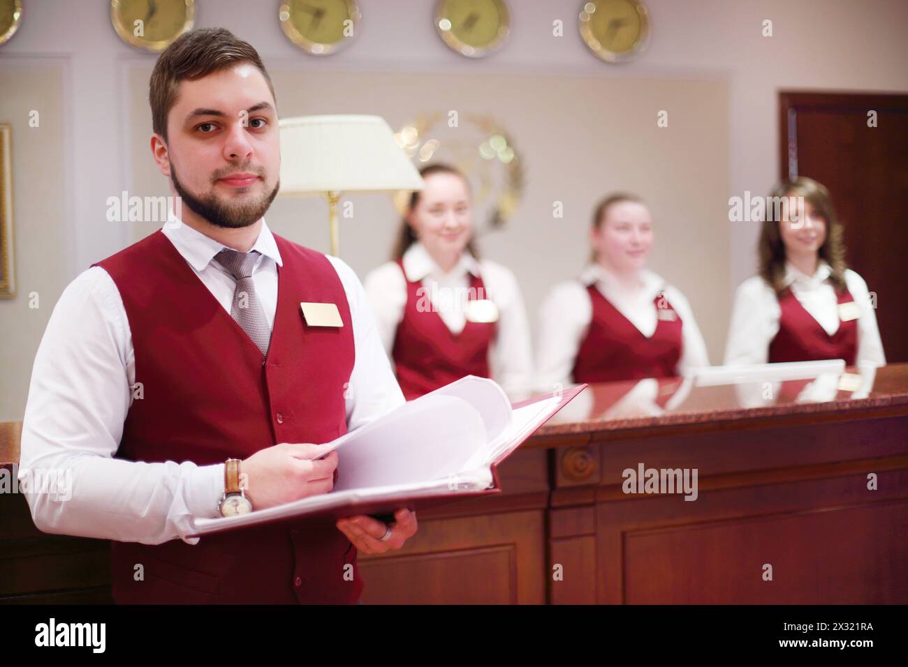 Receptionist man with folder . three woman at counter for guests in ...