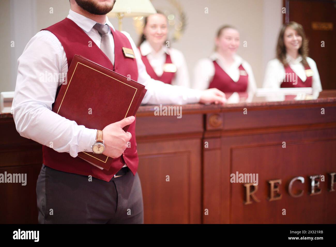 Receptionists at counter for guests in hotel, three woman and man Stock ...