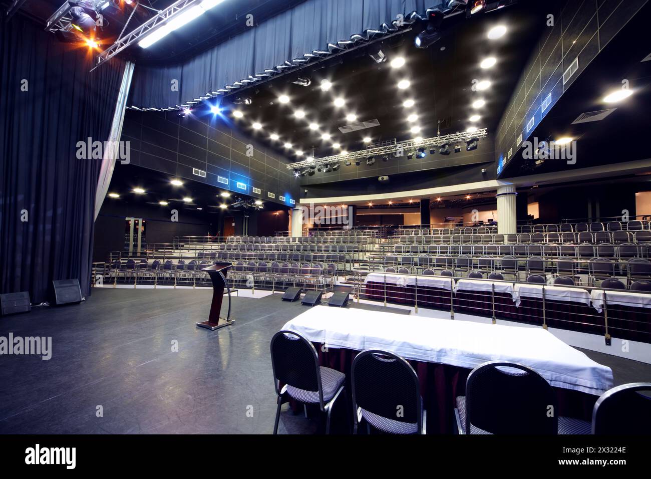 Document stand and table on stage and rows of seats in black hall for ...