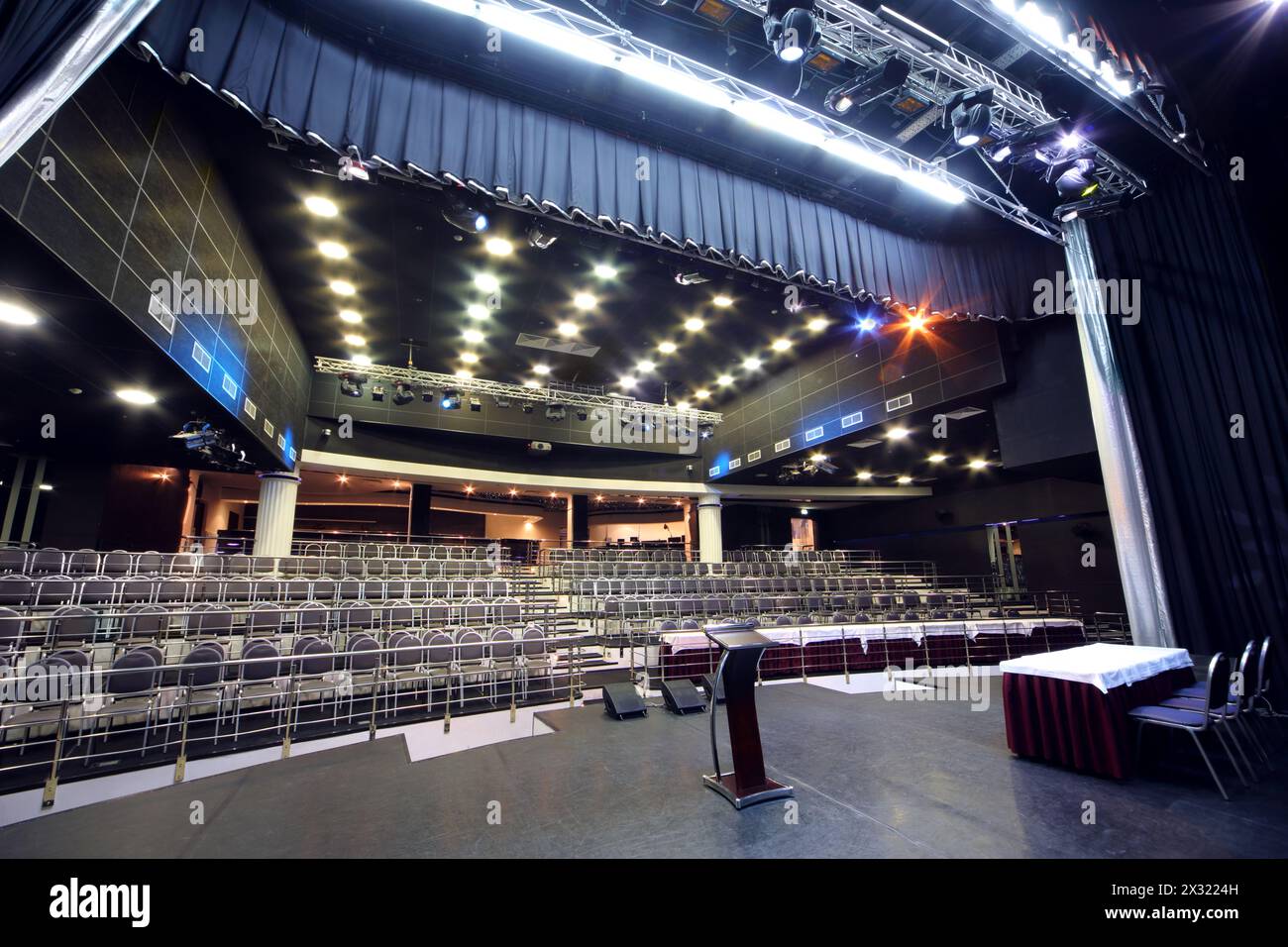 Document stand and table on stage and rows of seats in empty hall for ...