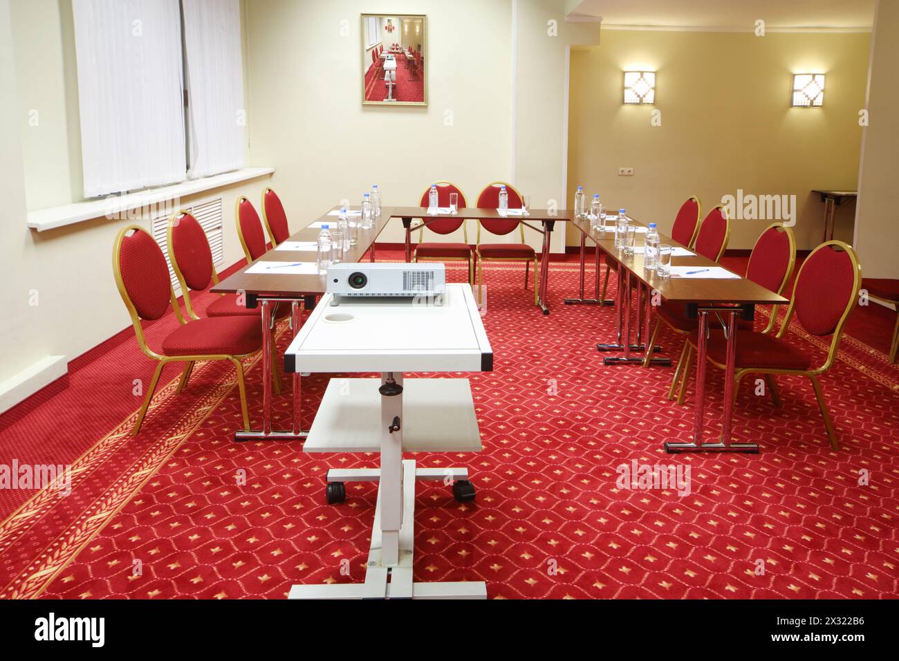 Projector, red chairs and tables in small room with red carpet for ...