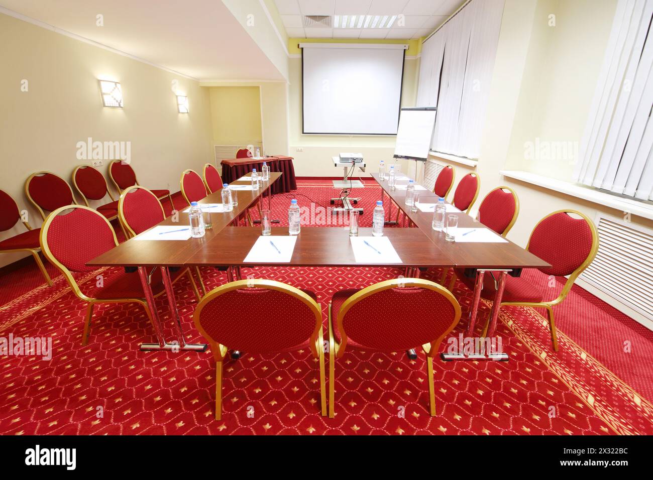 Projector, red chairs and tables with bottles in small room for ...