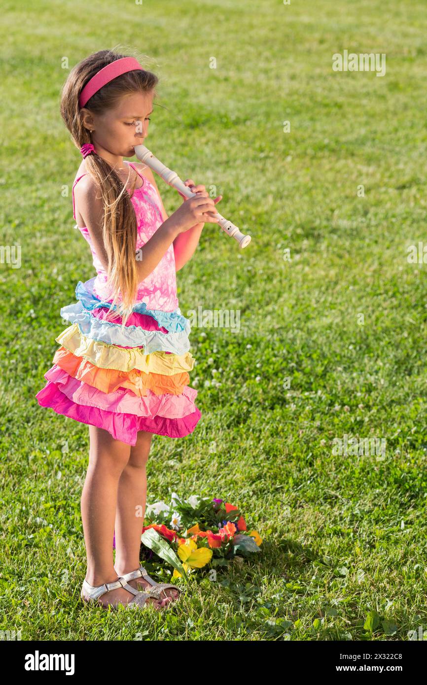 Little girl playing a fife on the green grass with flowers Stock Photo ...