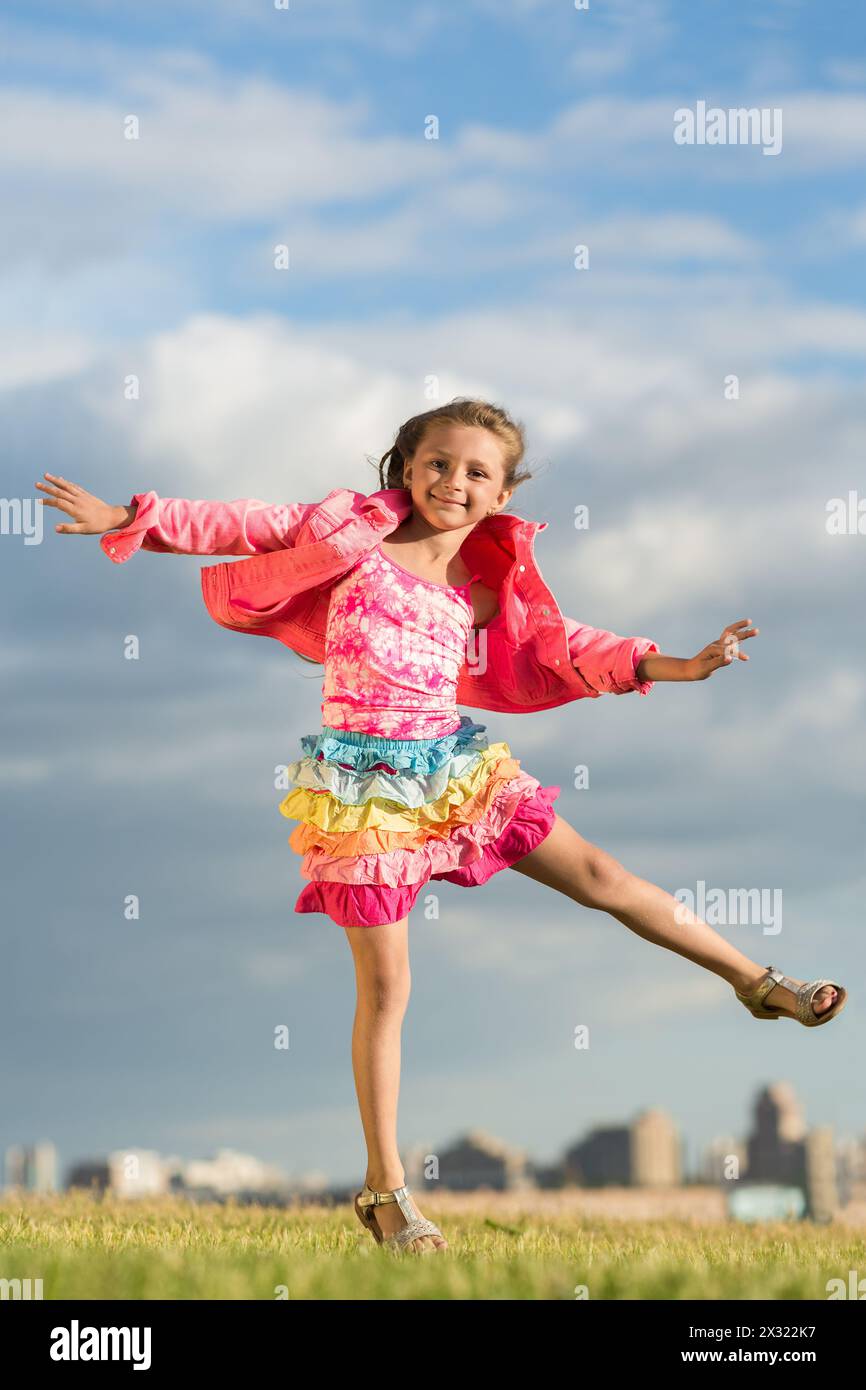 Little girl having fun and jumping in the grass on a background of ...