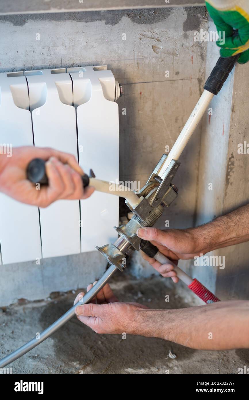 Workers crimping pipe heating system in the apartment Stock Photo - Alamy