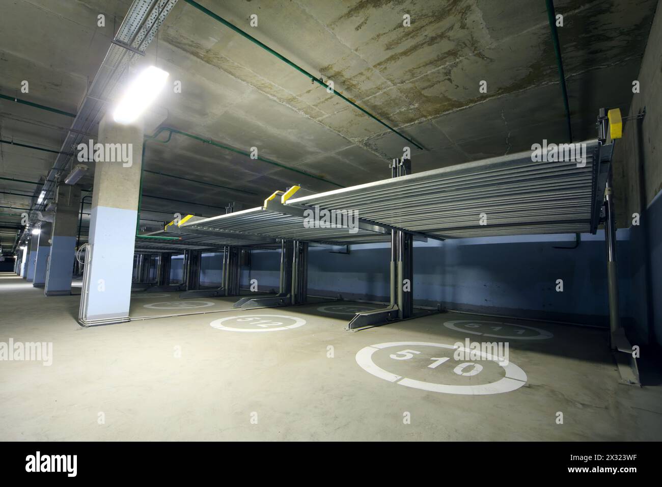 Long indoor two-level parking with electrolifts and concrete floor for ...