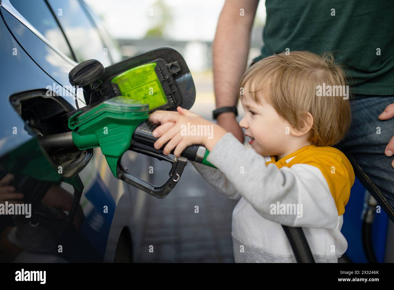 Cute little blond boy holding pump nozzle. Small funny kid helping ...