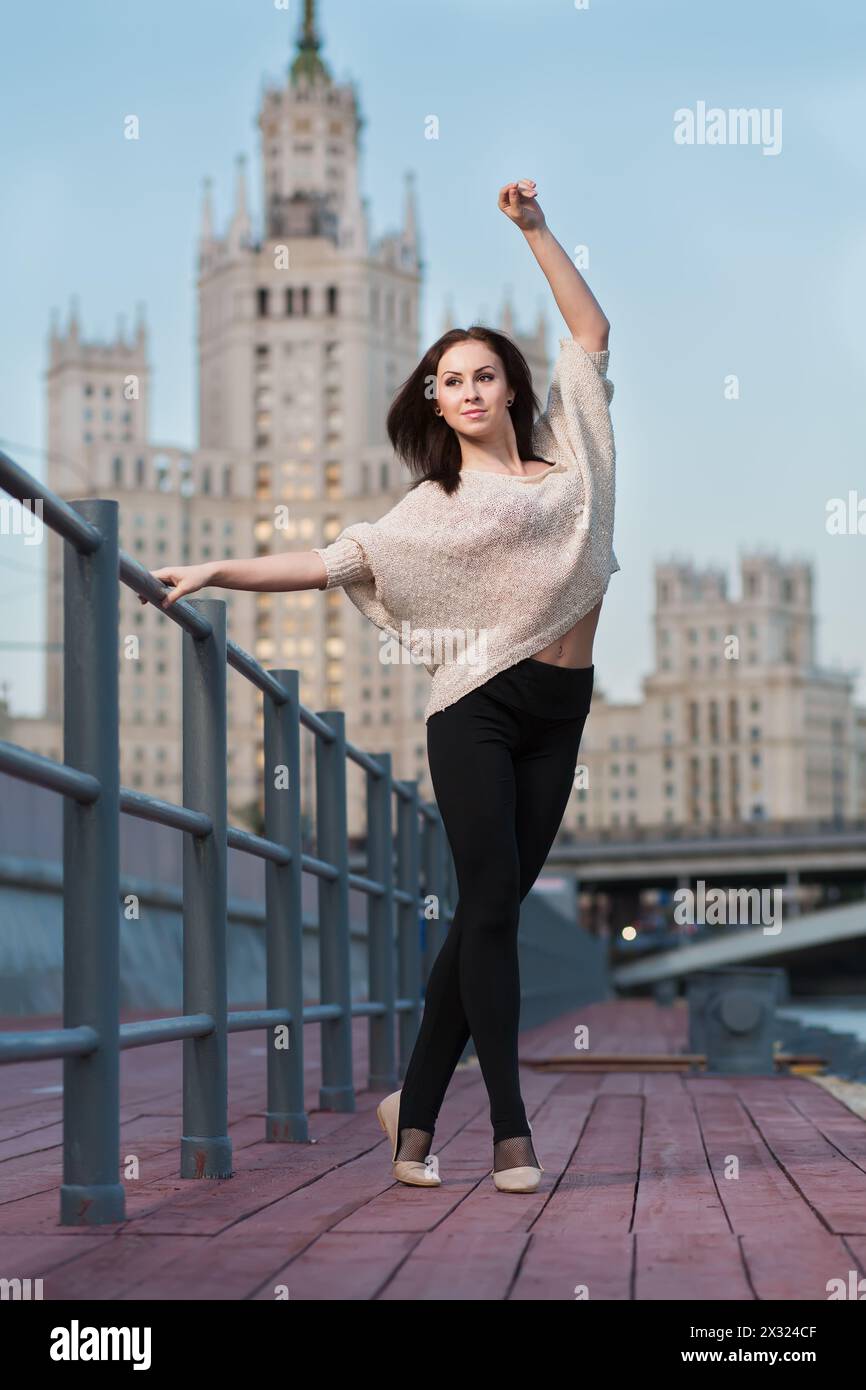 A young woman is standing in a ballet position using as a barre the ...