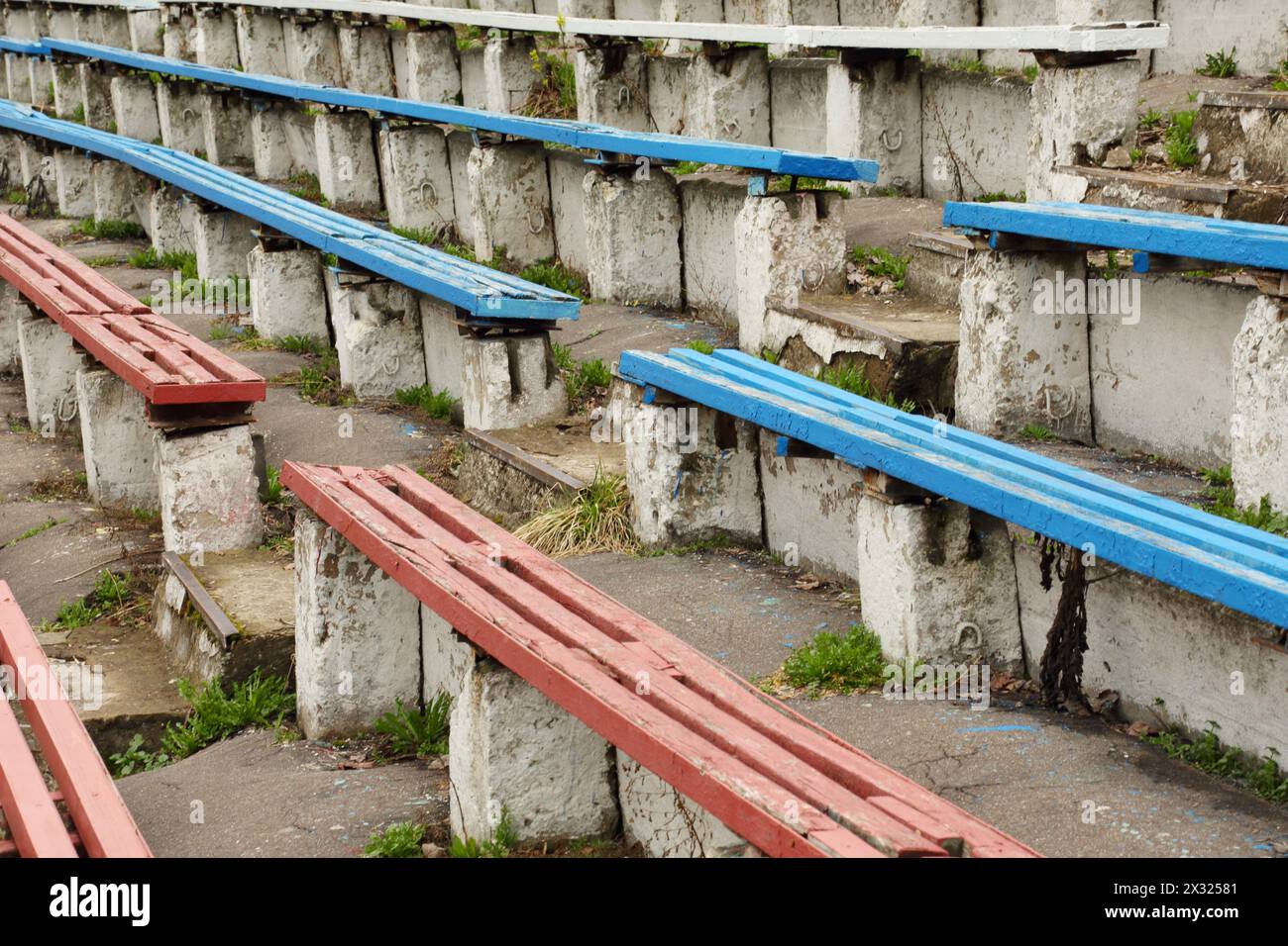 Long dirty destroyed blue and red grandstands and staircase at old ...