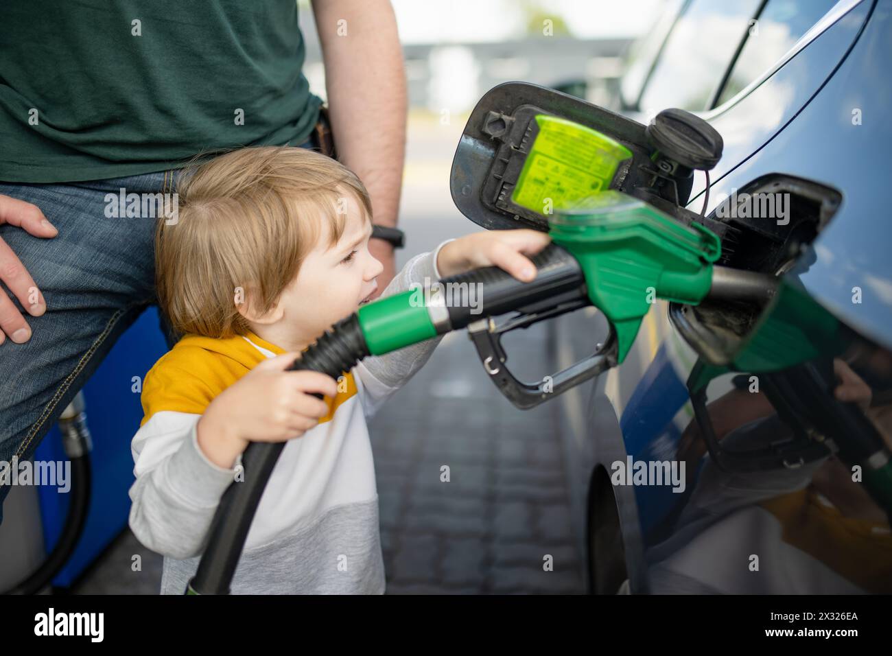 Cute little blond boy holding pump nozzle. Small funny kid helping ...