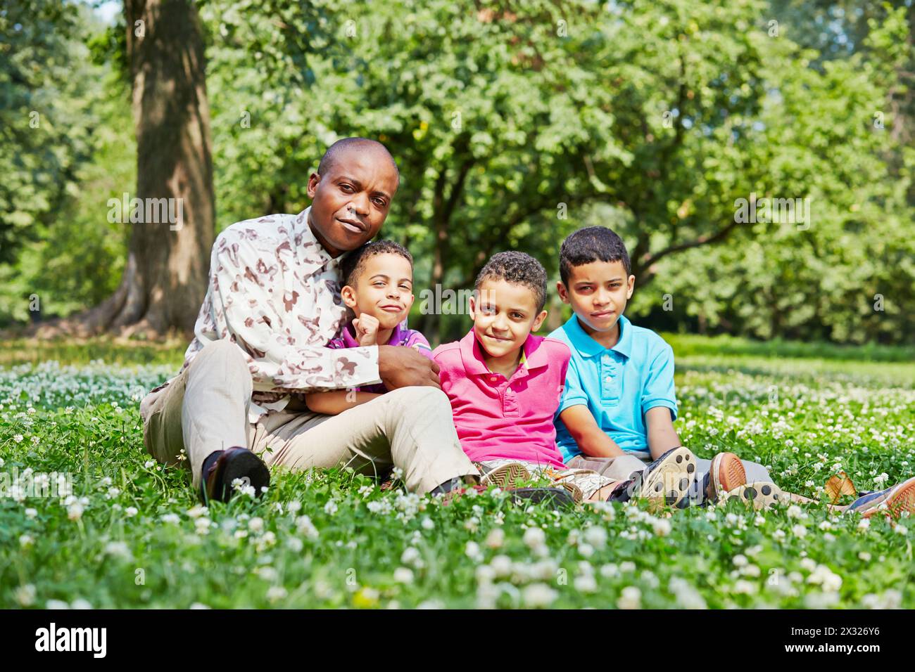 Father and three sons sit on ground in summer park Stock Photo - Alamy