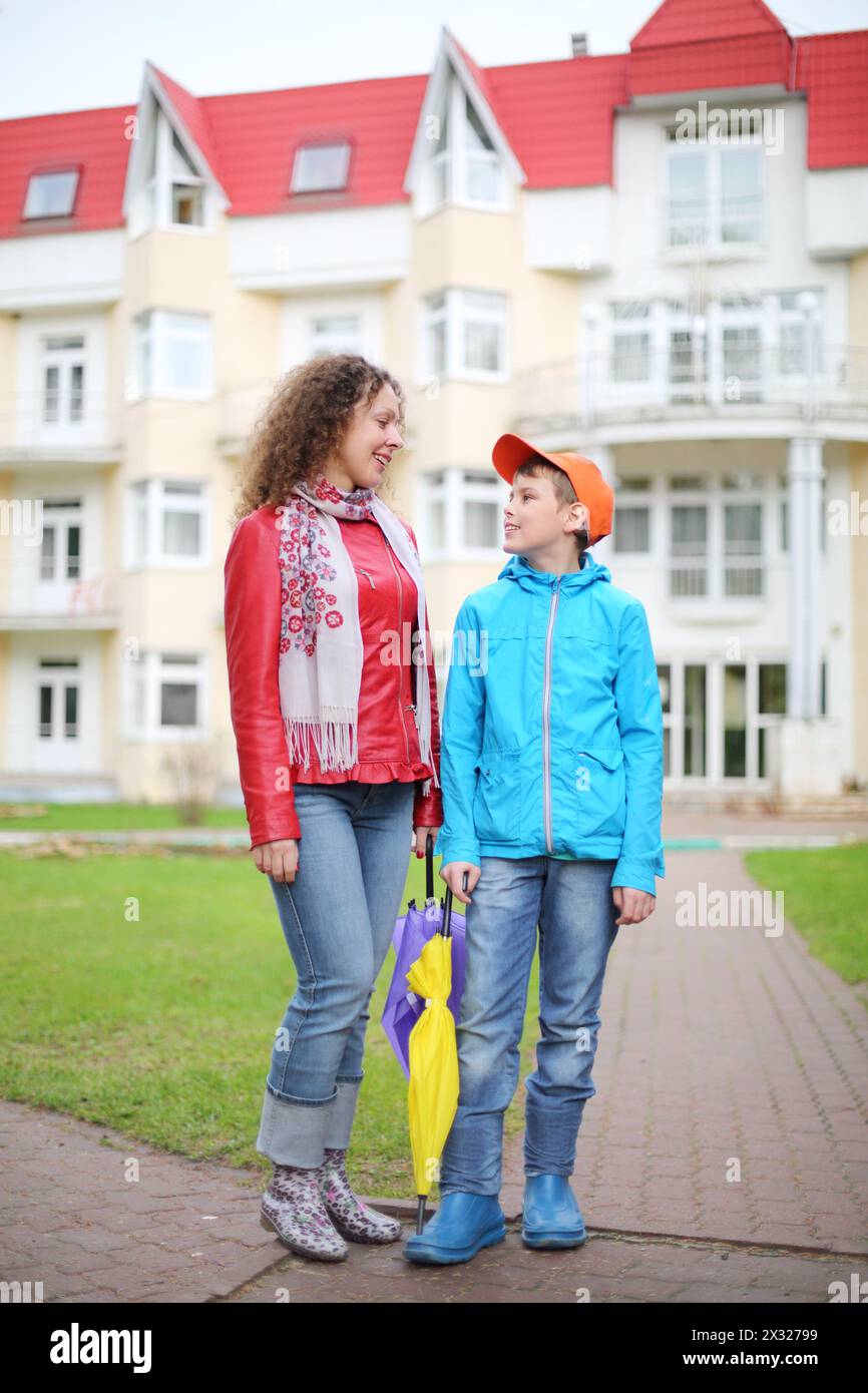 Mother and son with a canes umbrellas look at each other in the street ...