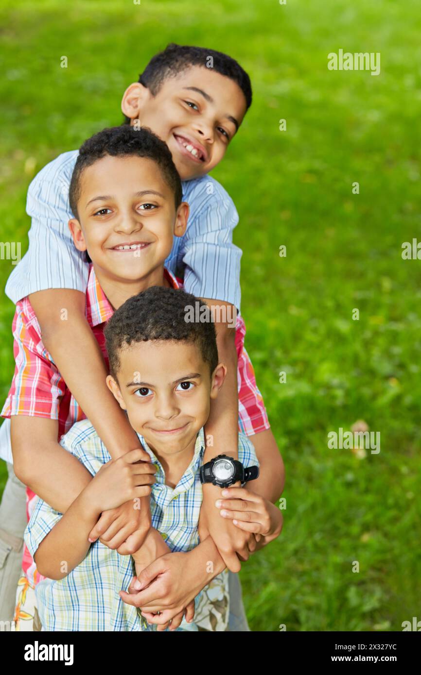 Half-length portrait of three smiling boys-brothers who stand one by ...