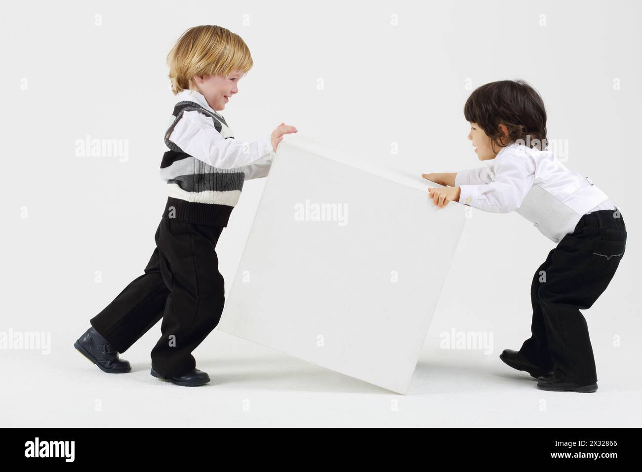 Two little boys reverse large white cube on white background Stock ...