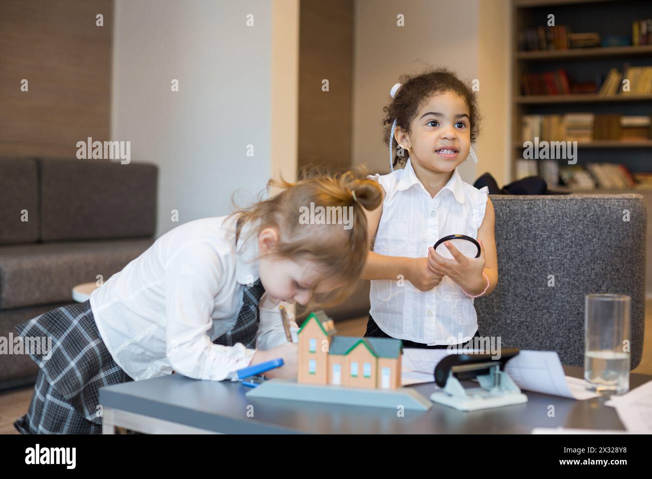 Two little girls in business suits with toy and stationery in a ...