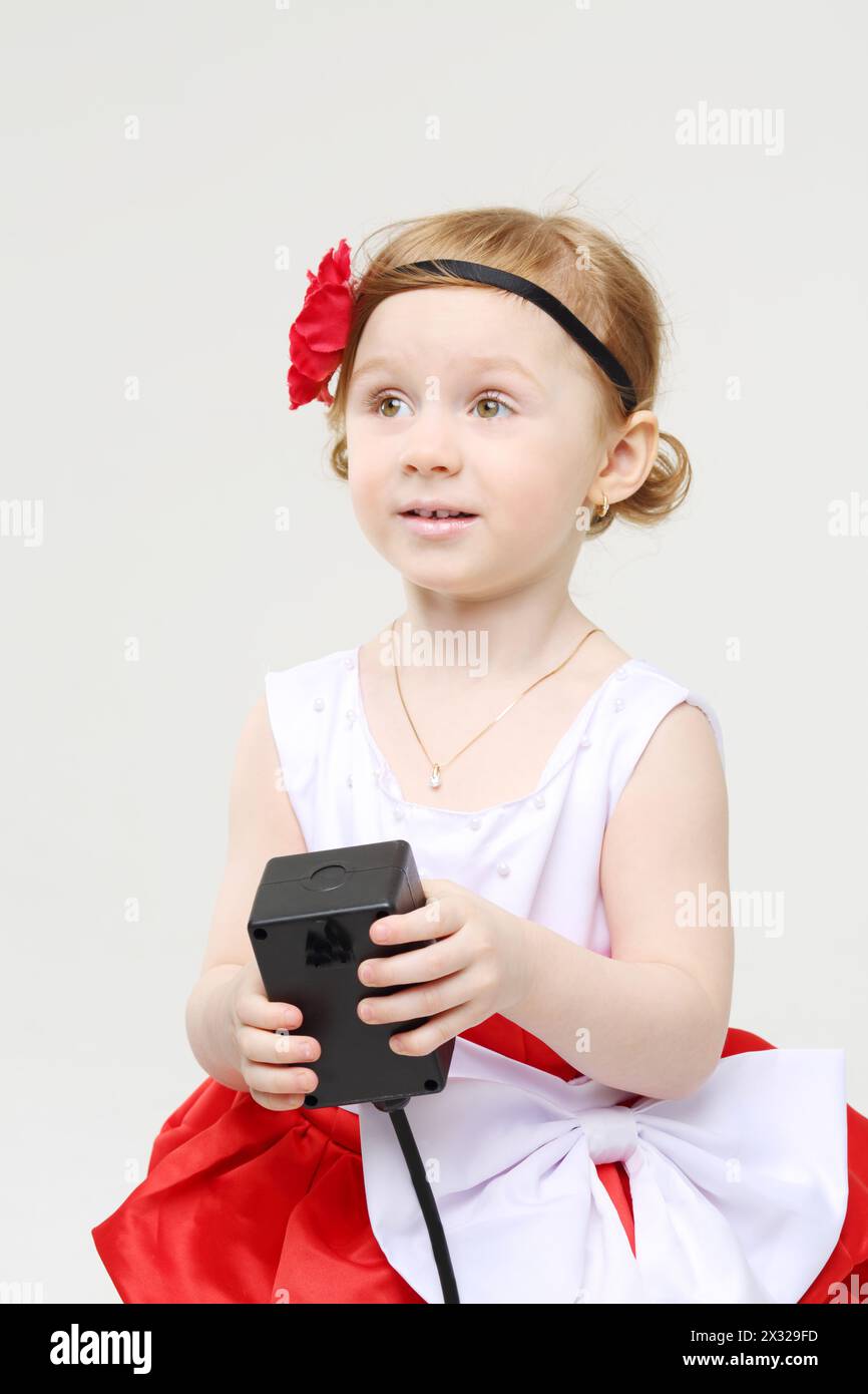 Little pretty girl holds black control console on white background ...