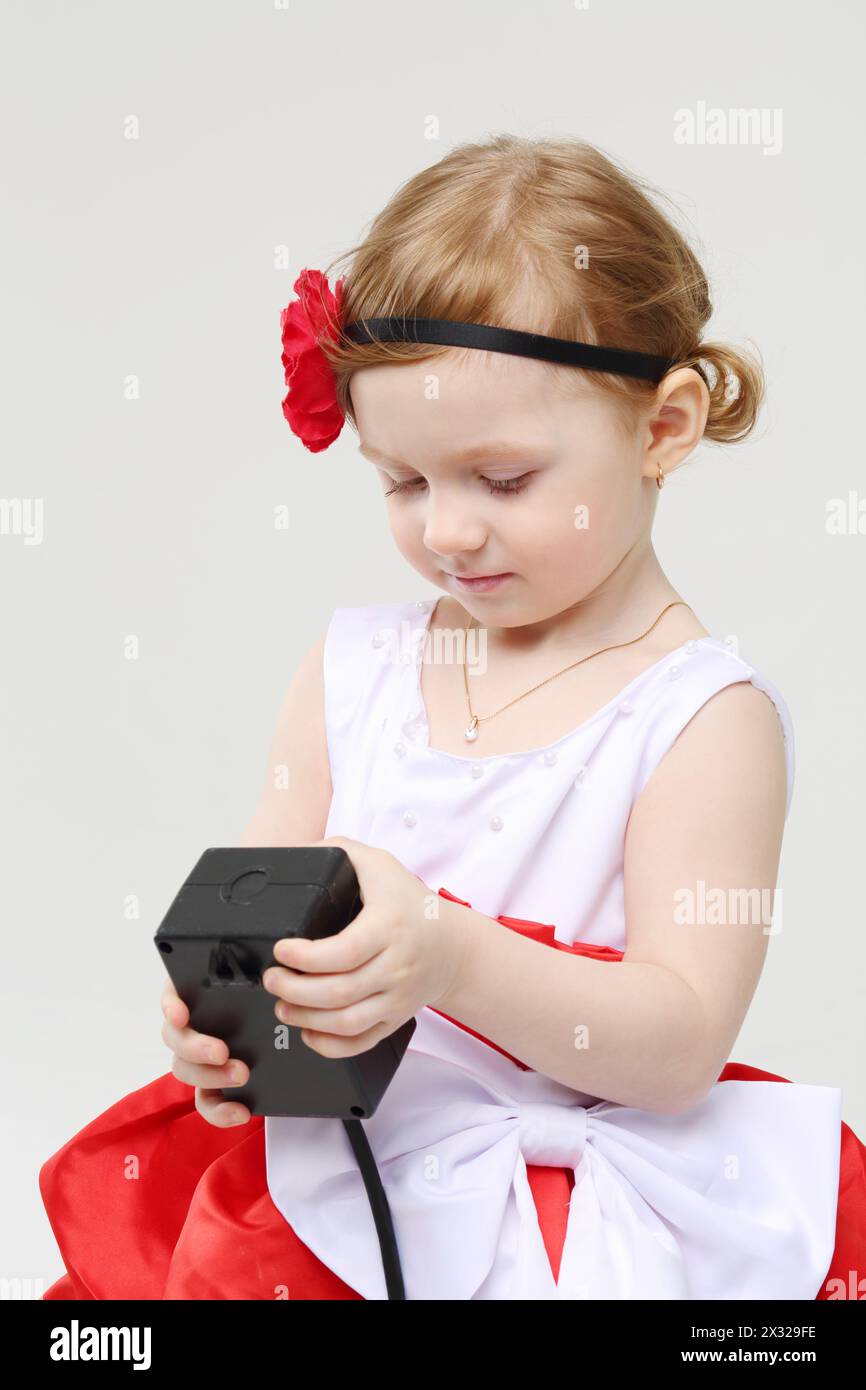 Little beautiful girl holds black control console on white background ...