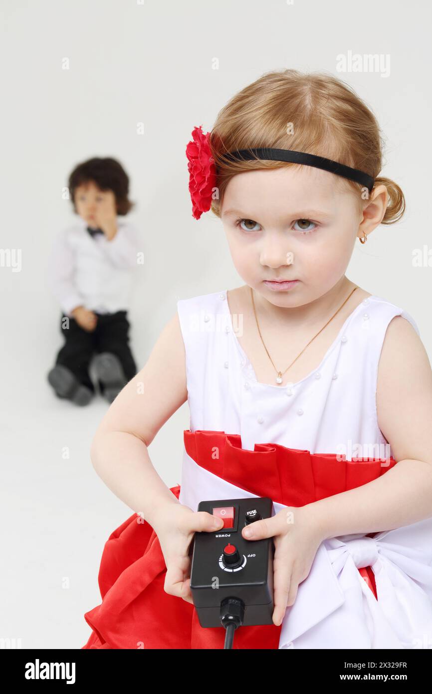 Little girl presses button on control console and boy sits behind she ...