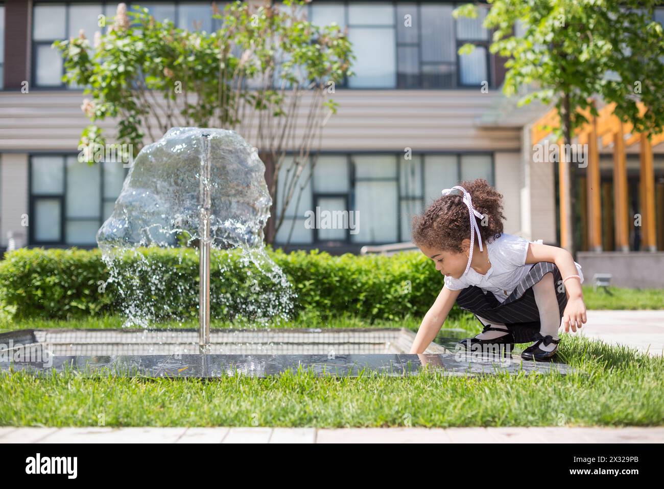 Girl mulatto draw water from the fountain in the park Stock Photo - Alamy